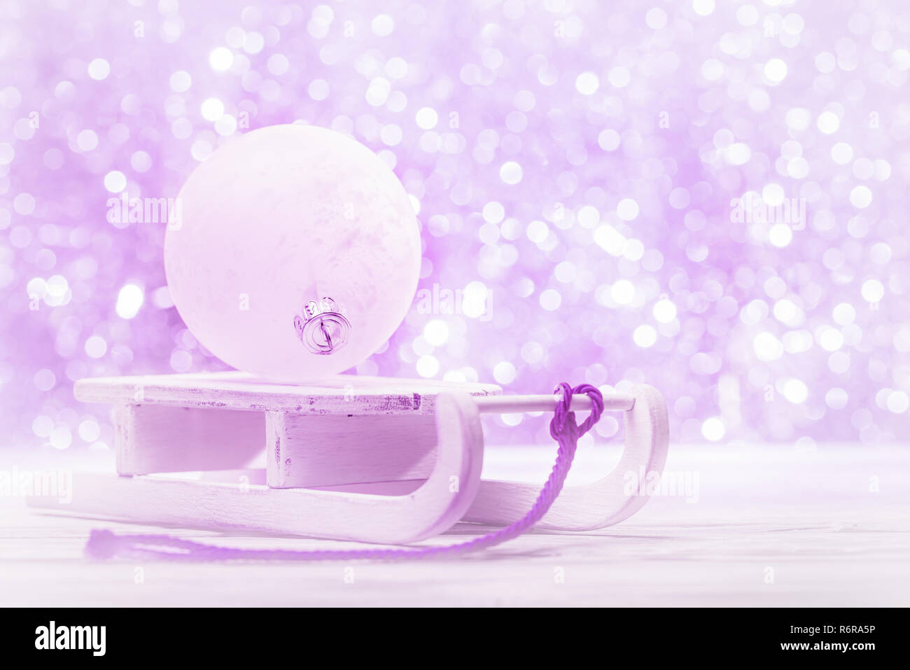 Glowing Christmas ball on sledge over holiday background, high key ...