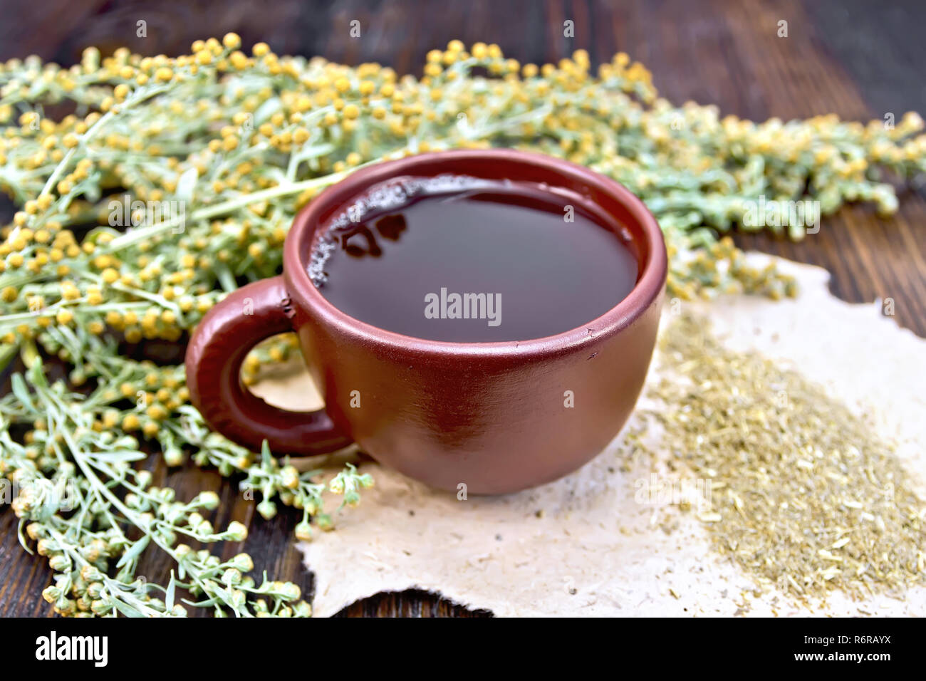 Herbal tea in a clay cup, twigs gray sagebrush, wormwood dried on rough ...