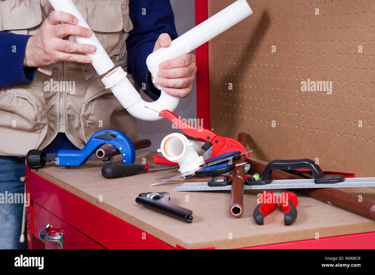 plumber at work on his workbench to fit pipes Stock Photo - Alamy
