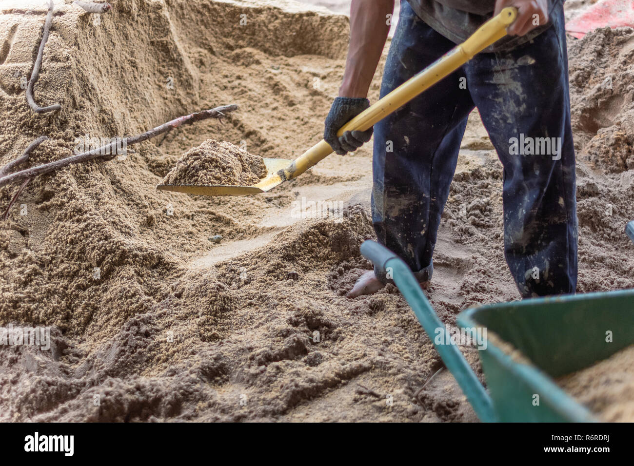 A worker use the shovel to fill the sand into the wheelborrow for ...