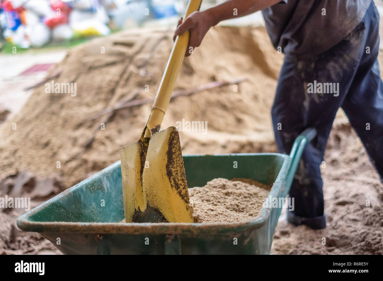 A worker use the shovel to fill the sand into the wheelborrow for ...