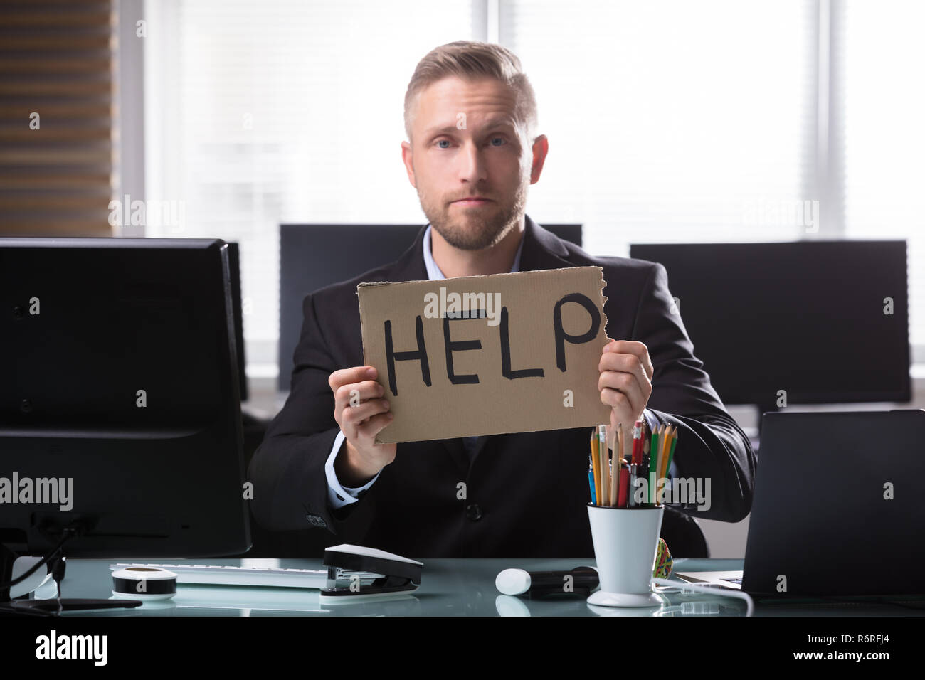 Businessman Holding Cardboard With Help Text Stock Photo - Alamy