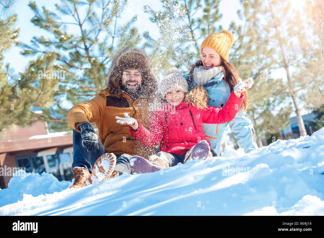 Winter vacation. Family time together outdoors sitting throwing snow ...
