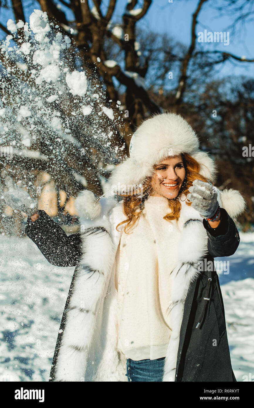 Beautiful young winter woman smiling and playing snowballs outdoors ...