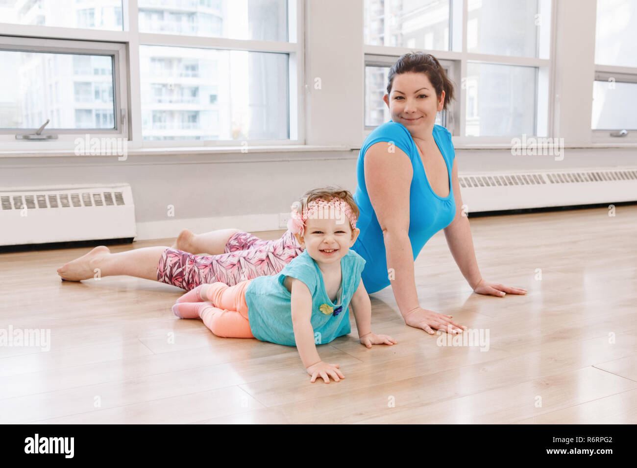 Young woman with child daughter doing workout in gym class to loose ...