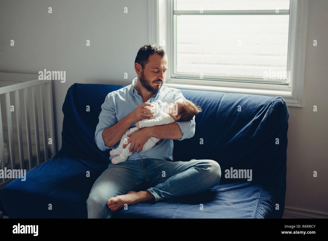 Portrait of middle age Caucasian father feeding newborn baby son ...