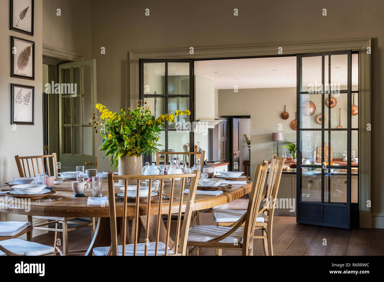 Wooden breakfast table and framed botanc artwork in split level kitchen ...