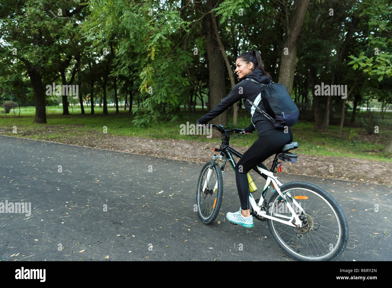 Image of a beautiful woman walking on bicycle in the park outdoors ...