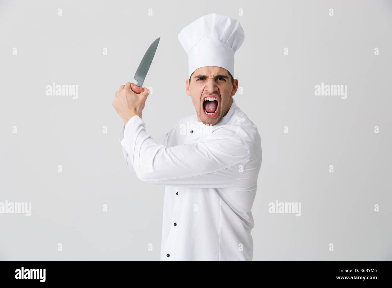 Photo of emotional agressive screaming young man chef indoors isolated ...