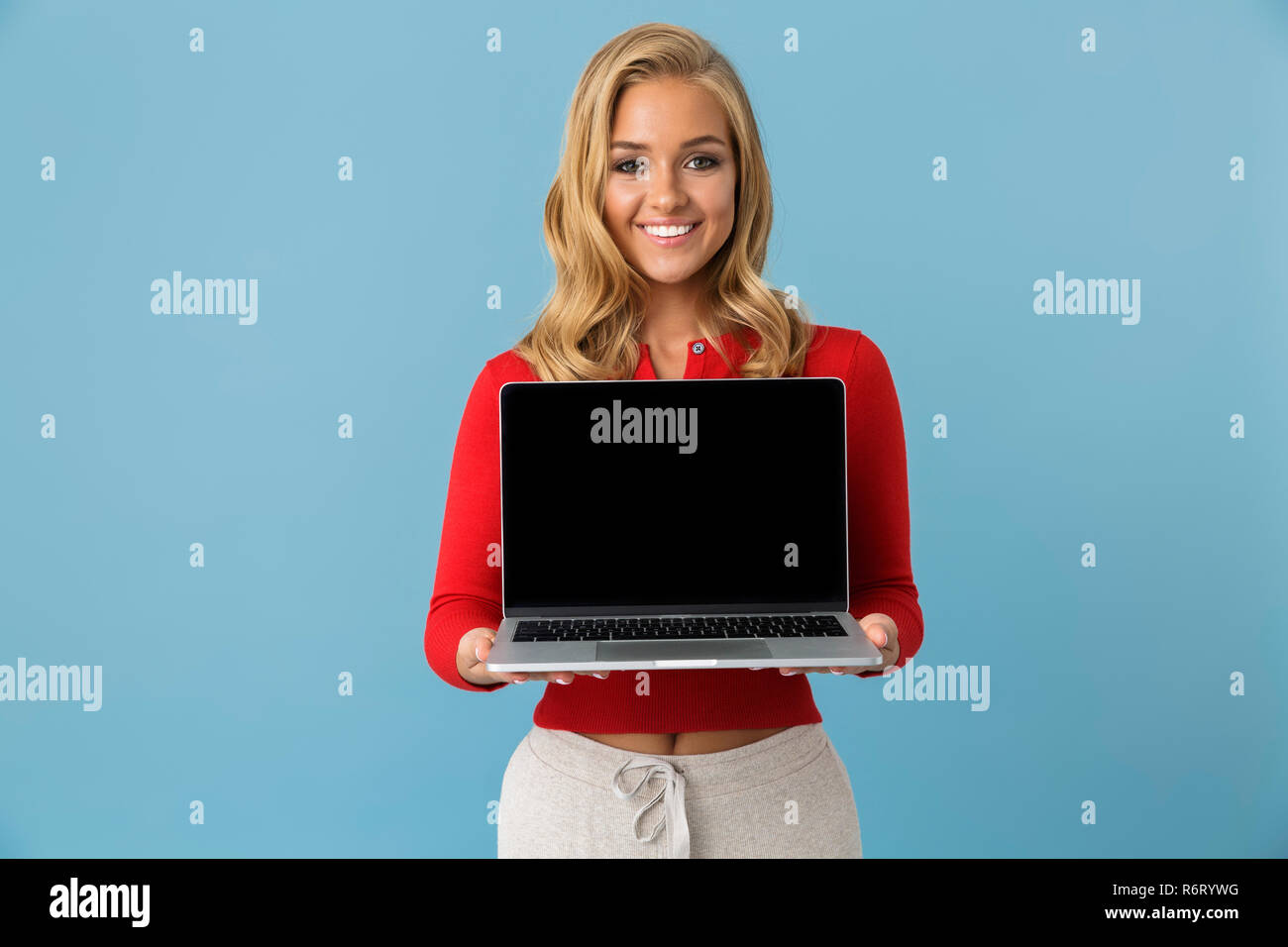 Portrait of young woman 20s holding laptop and demonstrating copyspace ...