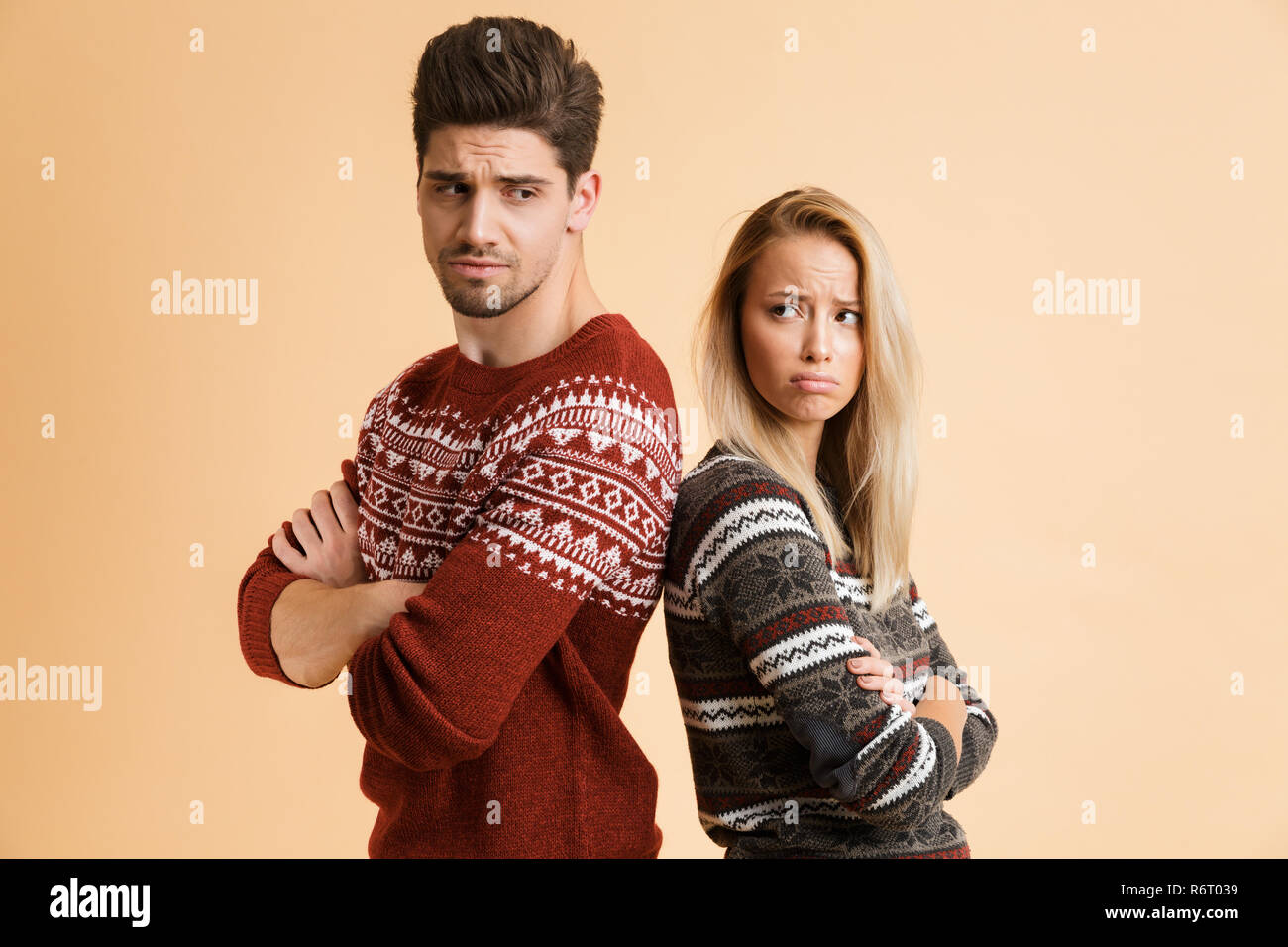 Portrait of a disappointed young couple dressed in sweaters standing ...