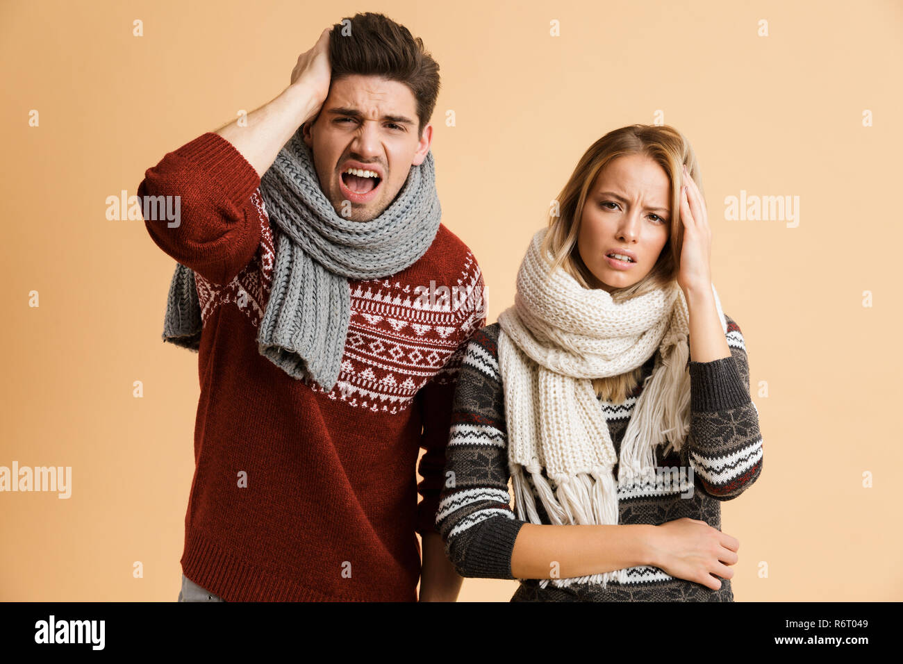 Portrait of a sick young couple dressed in sweaters and scarves ...