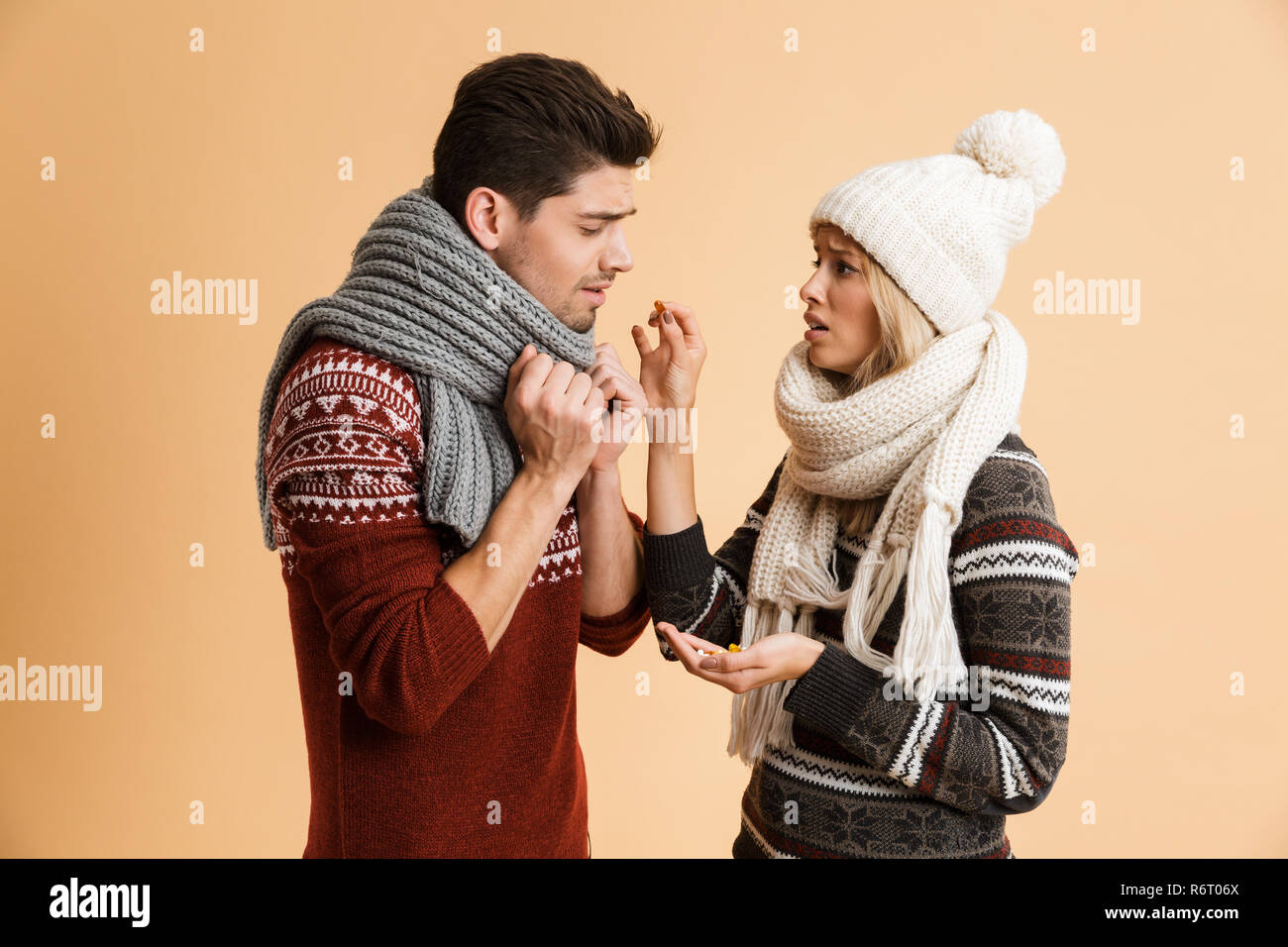 Portrait of a sick young couple dressed in sweaters and scarves ...