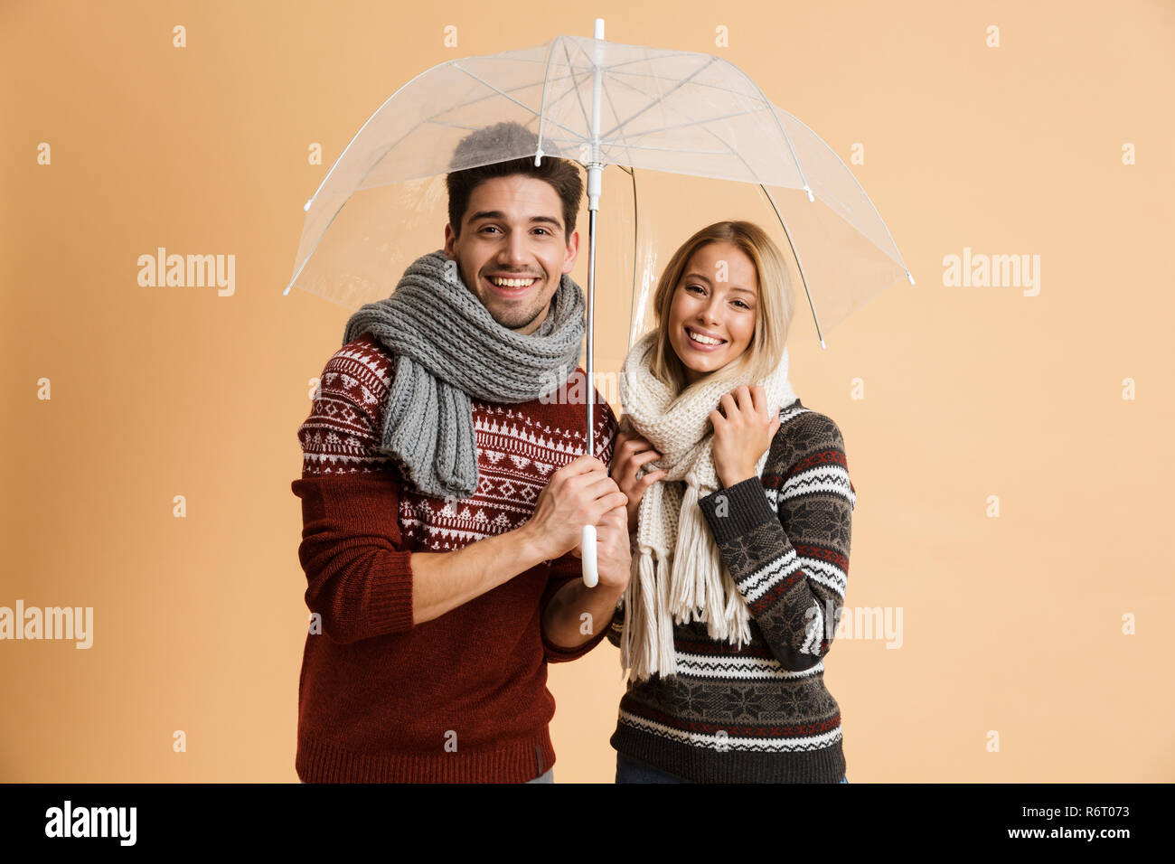 Portrait of a happy young couple dressed in sweaters and scarves ...