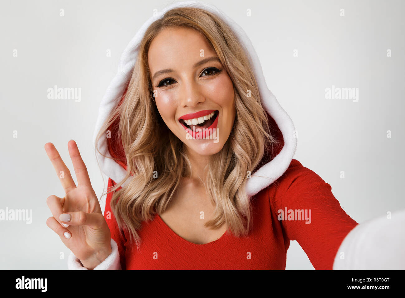 Portrait Of A Joyful Blonde Woman Dressed In Red New Year Costume Standing Isolated Over White