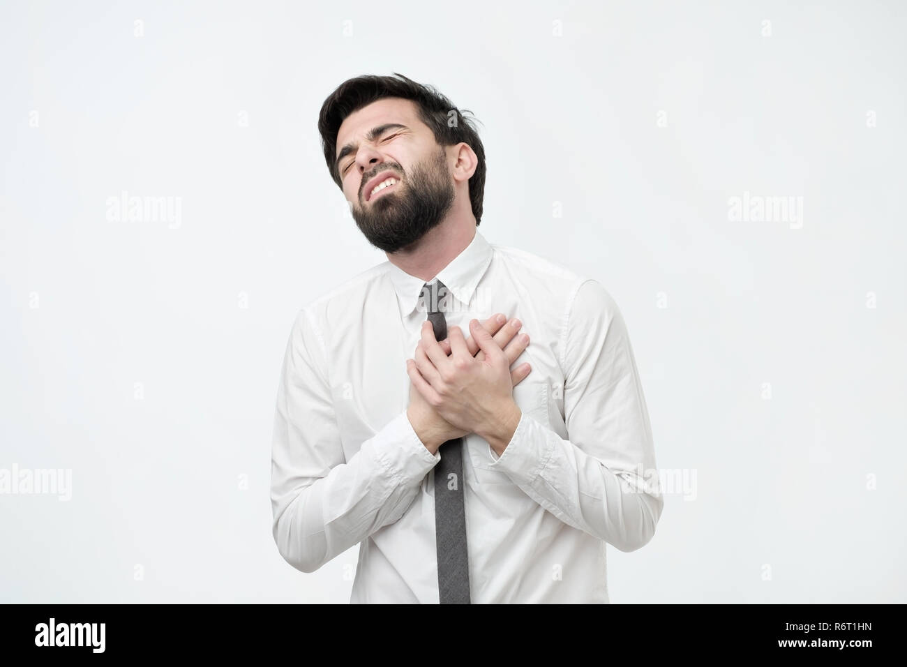 Young man having heart attack on white background Stock Photo - Alamy