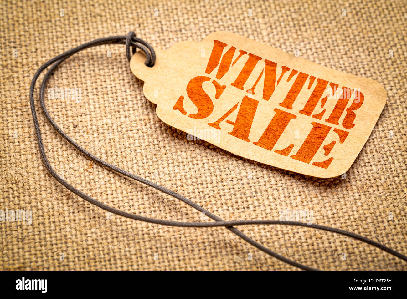 winter sale sign - red stencil text on a paper price tag against burlap ...