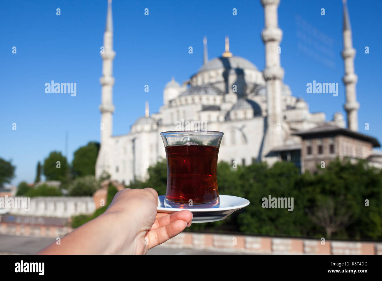Woman holding cup of traditional Turkish tea on terrace with view of ...
