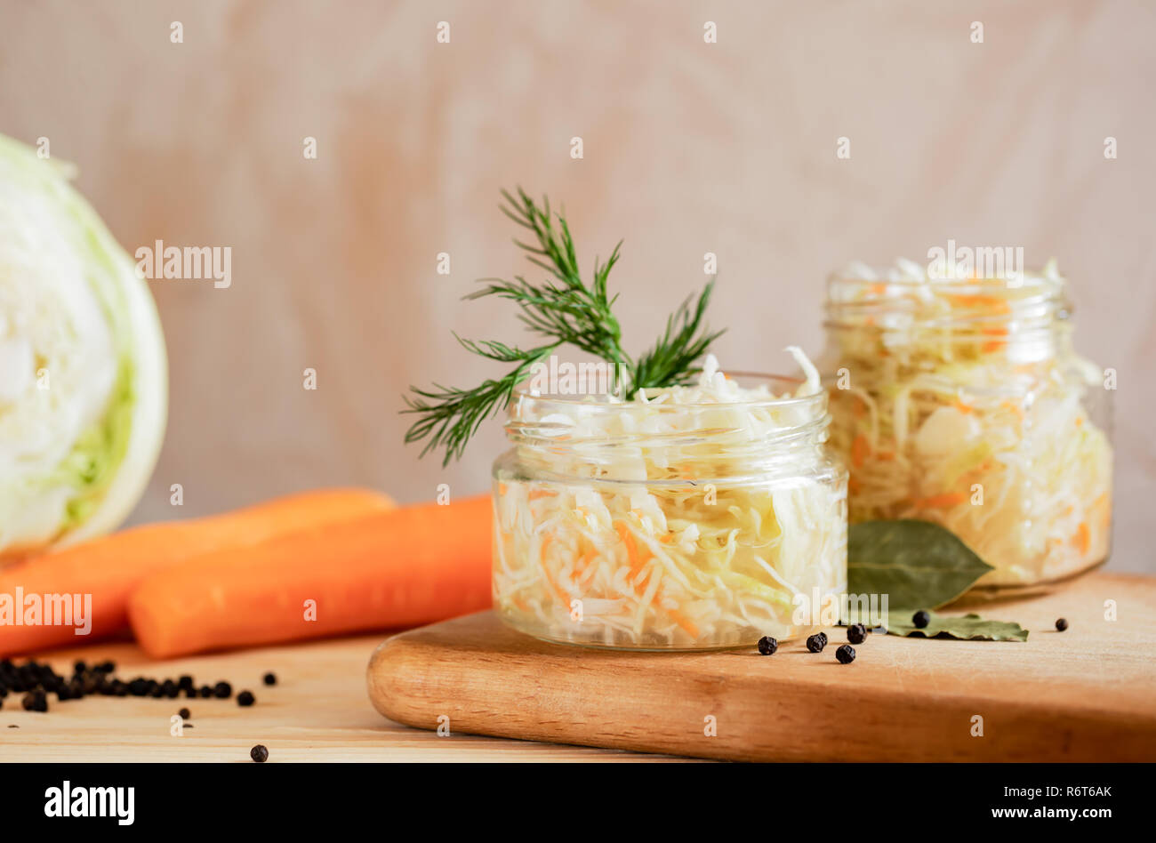 Glass jars with pickled cabbage and ingredients for its preparation ...