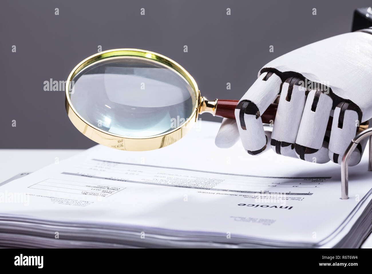 Robot Holding Magnifying Glass Over Invoice Stock Photo - Alamy