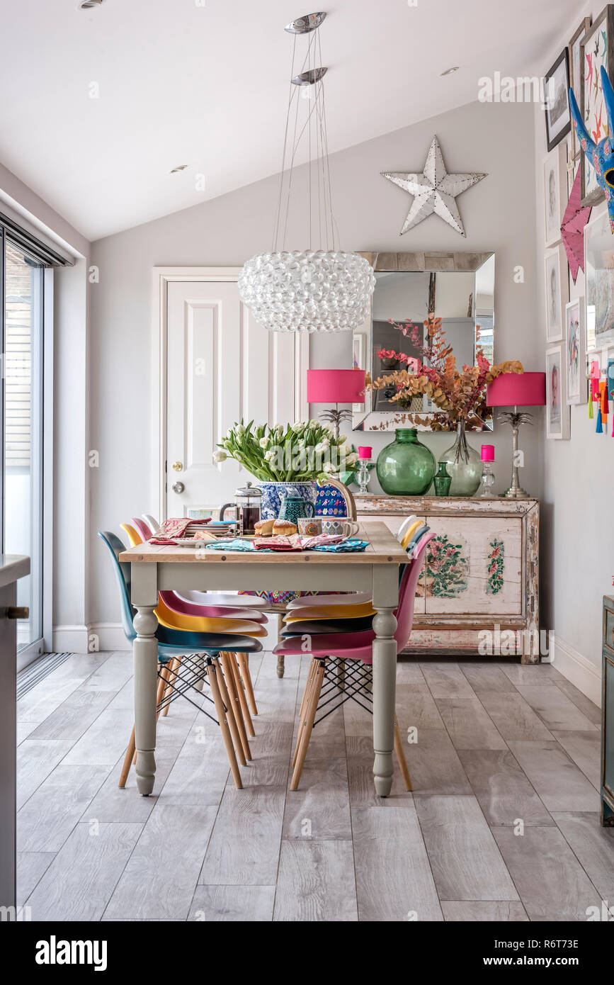 Caboche pendant above table with multicoloured Eames-style chairs Stock ...