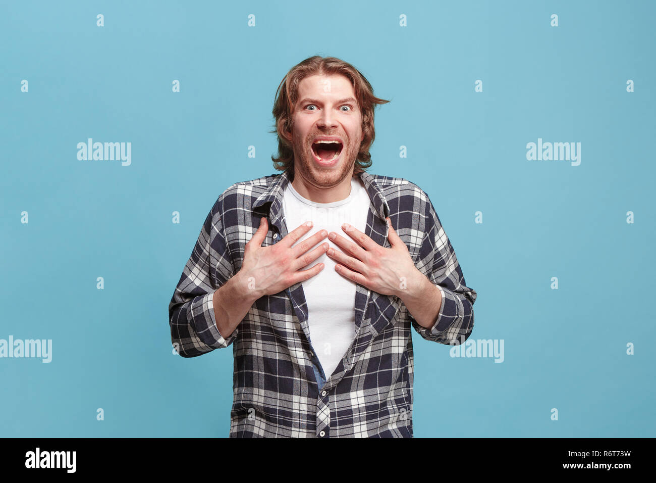 Beautiful man looking suprised isolated on blue Stock Photo - Alamy