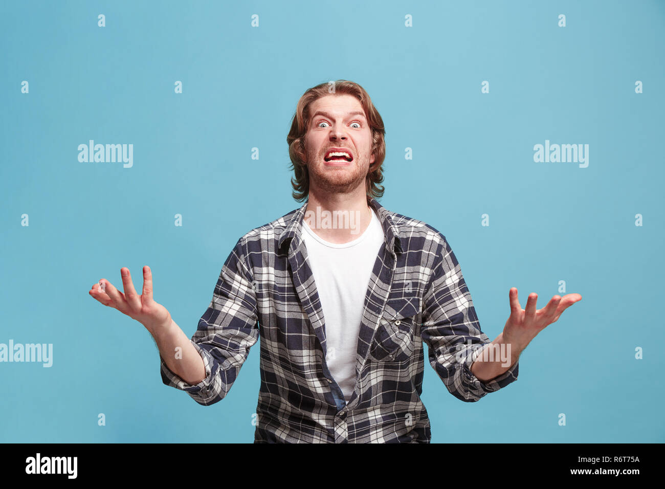 The young emotional angry man screaming on blue studio background Stock ...