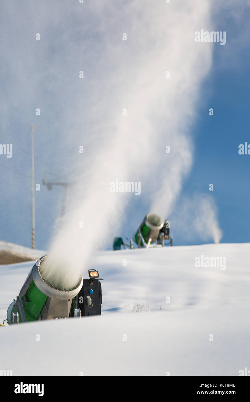 Snow-machine bursting artificial snow over a skiing slope to alow for ...