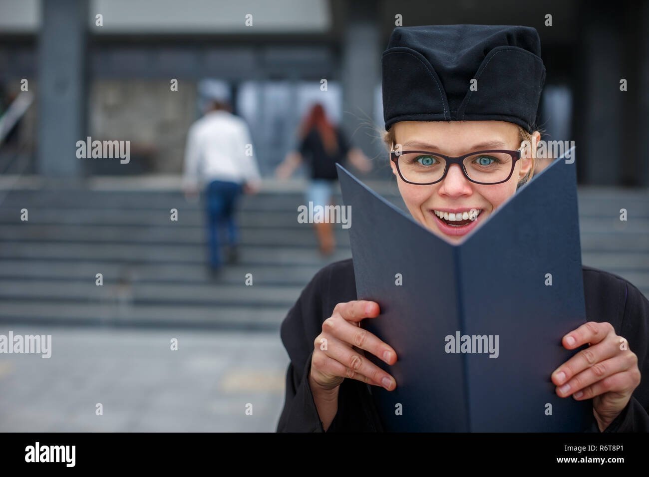 Pretty, young woman celebrating joyfully her graduation - spreading ...