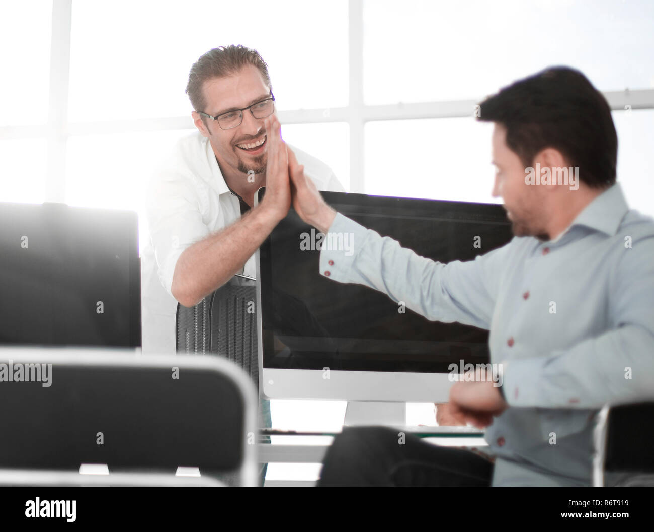 employees give each other a high five over the computer Desk Stock ...