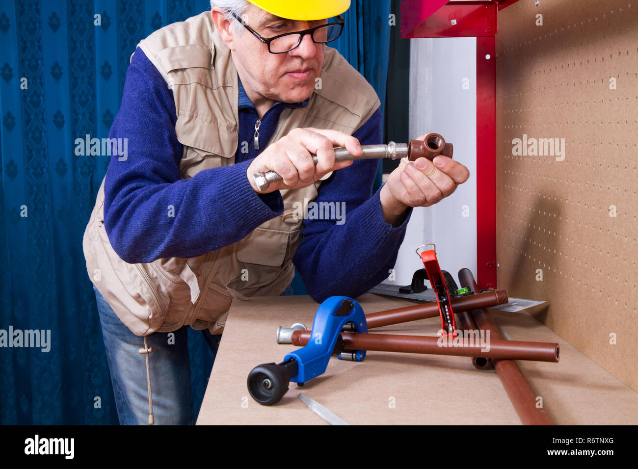 plumber at work on his workbench to fix pipes Stock Photo - Alamy