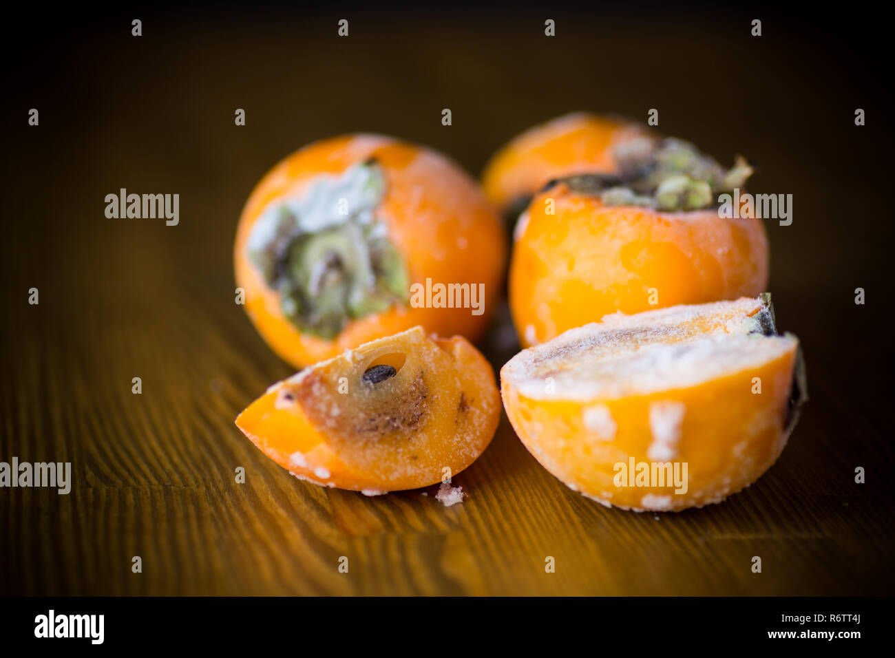 frozen ripe persimmon in ice on wooden Stock Photo - Alamy