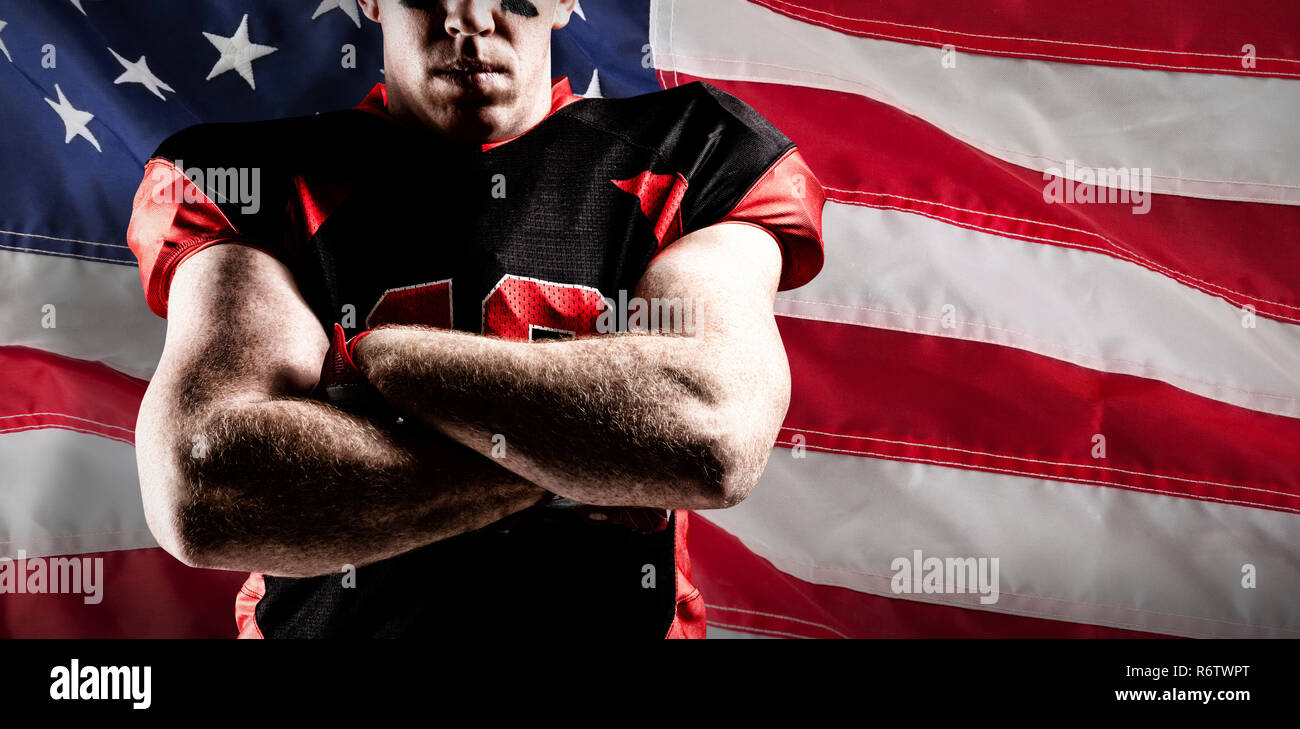 American football player standing with arms crossed against close-up of ...