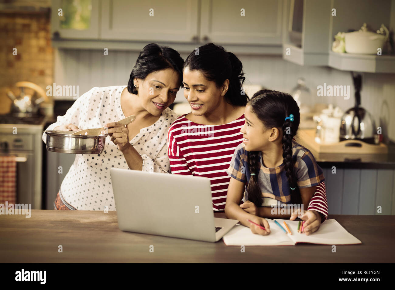 Multi-generation family using laptop in kitchen Stock Photo - Alamy