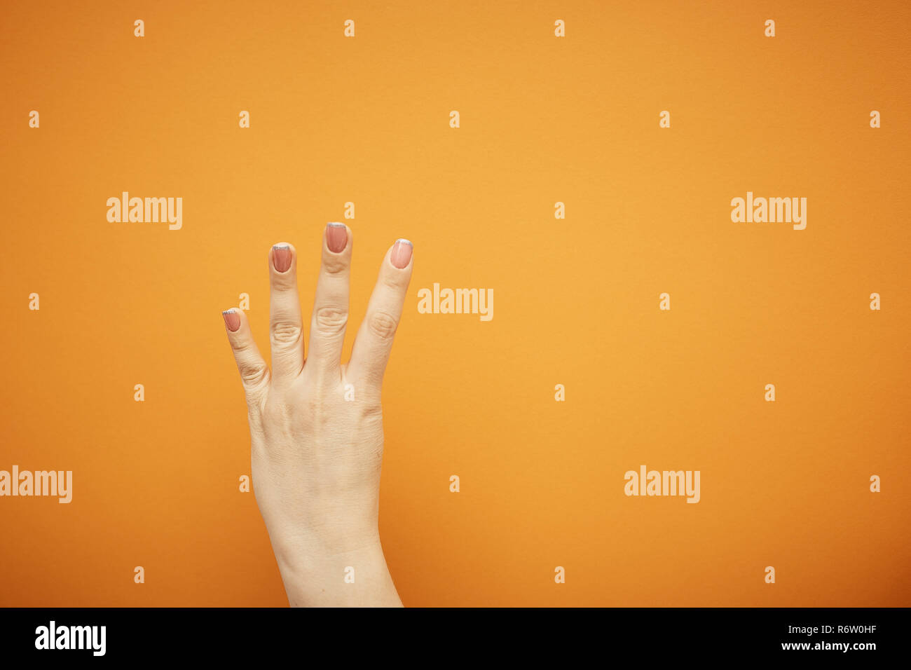 gesture, female hand shows four fingers isolated on orange background ...