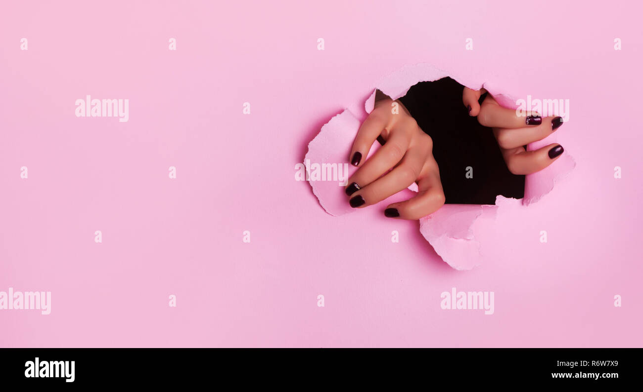 Female hands tearing hole in pink paper Stock Photo - Alamy