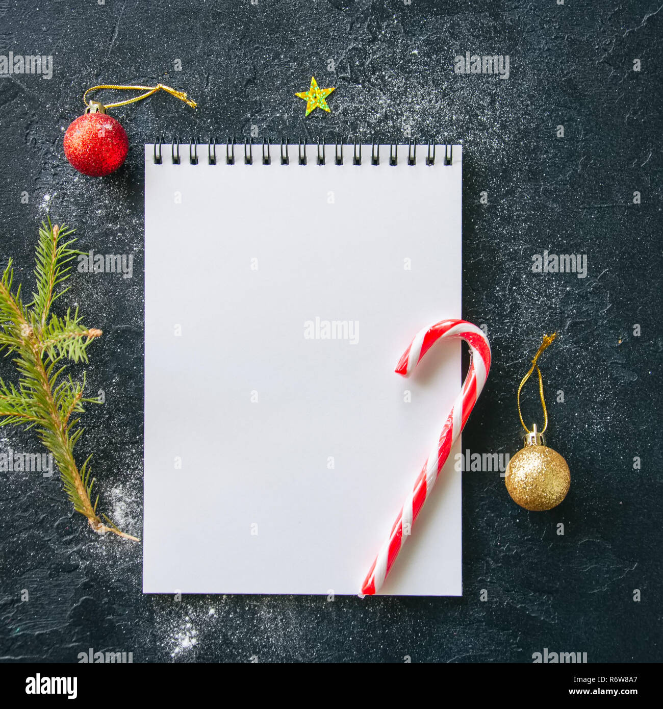 Empty white page of notepad, fir tree branch, candy cane, balls on a ...