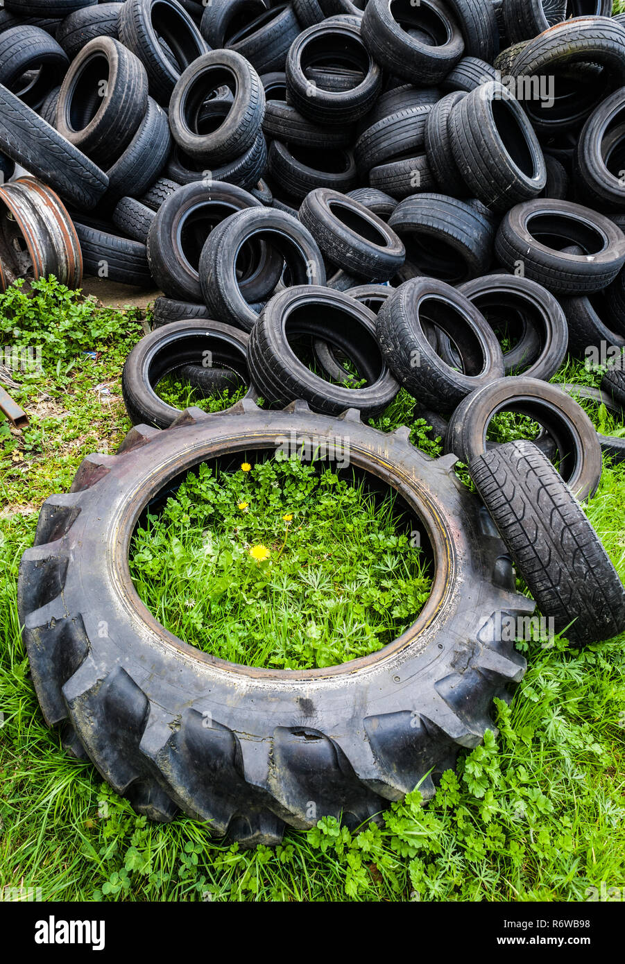 pile of worn car and tractor tires piled up in a grass field Stock ...