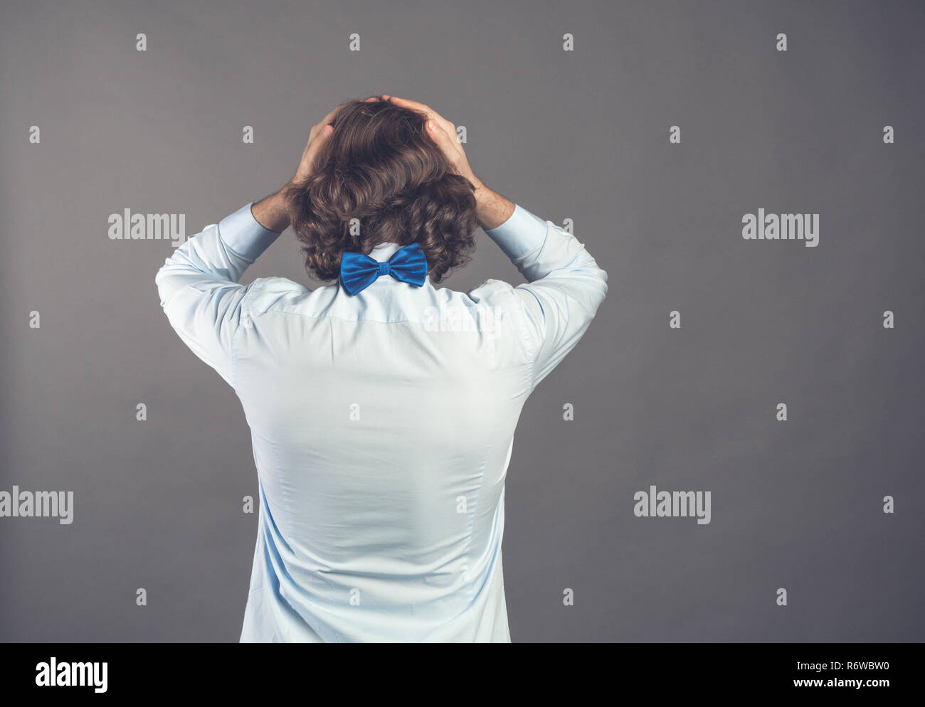 Backside view standing young man with shaggy curly hair wearing blue ...
