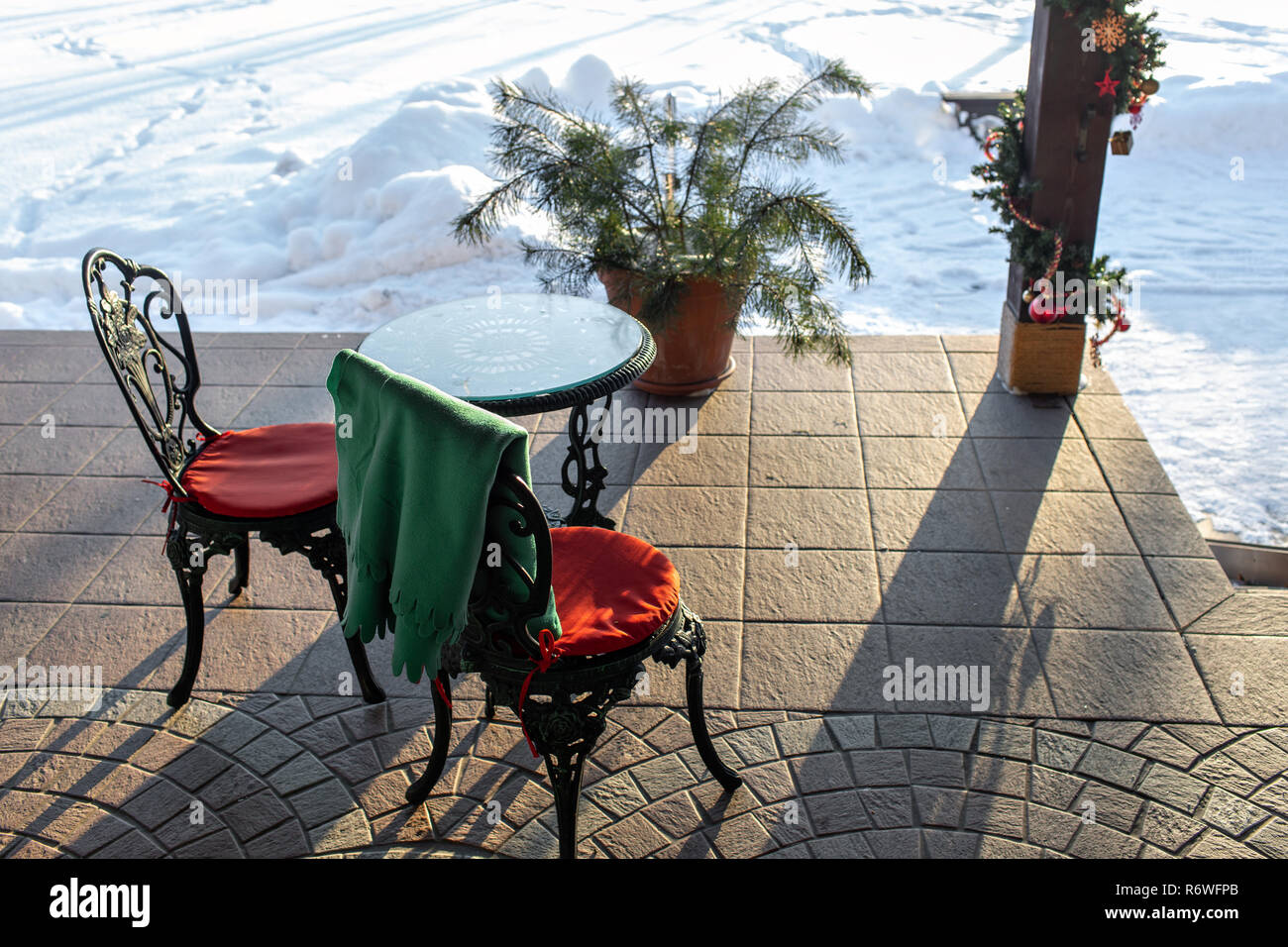 Cast iron chairs and tables with pillows and a blanket on restaurant ...