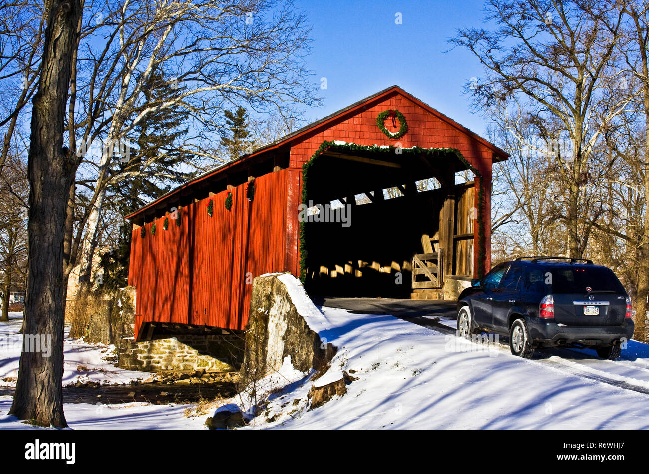 Winter snow scene of a car driving through a red covered bridge in ...