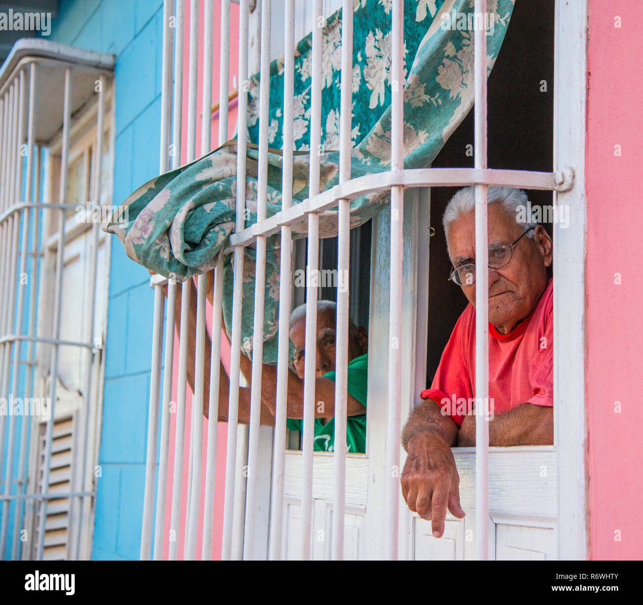 Two men watching people on the street from the window of their home in ...