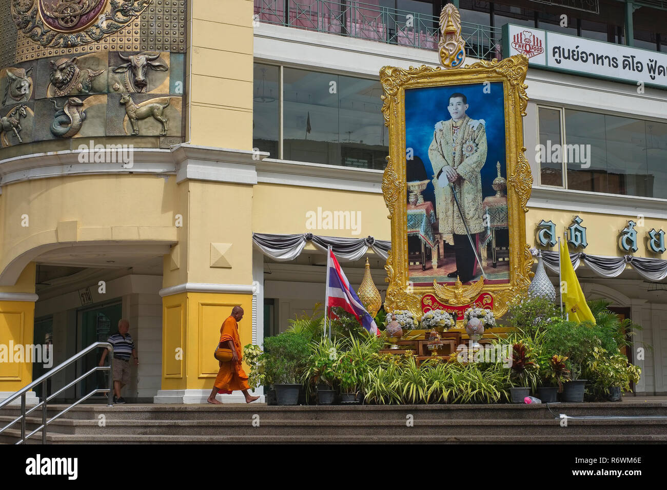 A Buddhist monk walks under a large portrait of Thai king Maha ...