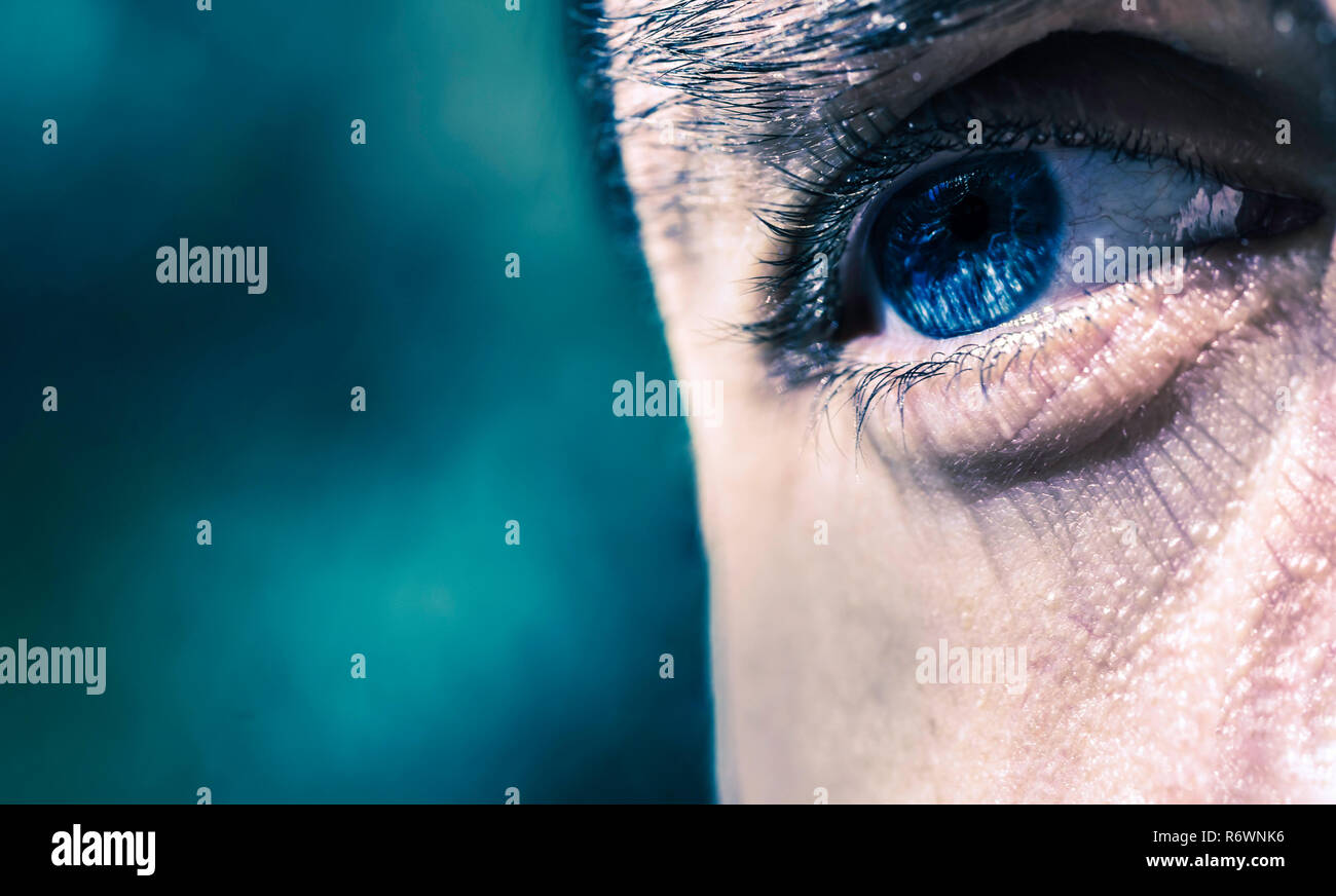 A single blue eye as a cyclope on blue background illuminated by the ...