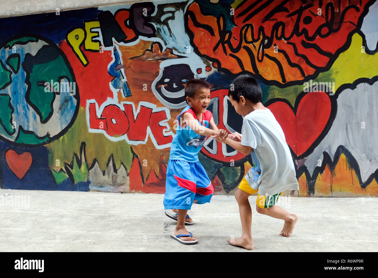 Street kids children are spinning in front of a graffiti wall at the ...