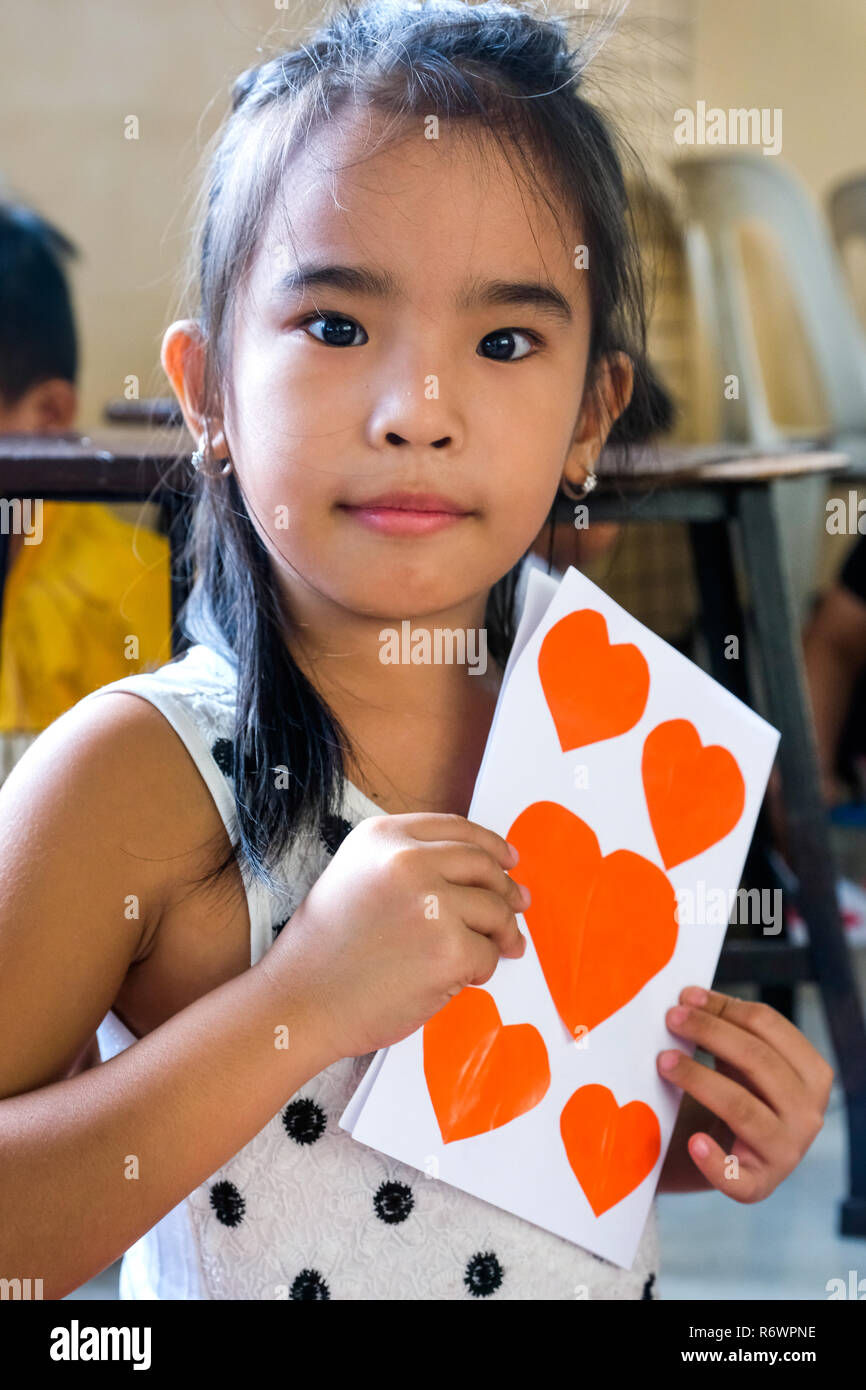 A girl is making a greeting card gift with red hearts for Valentine's ...