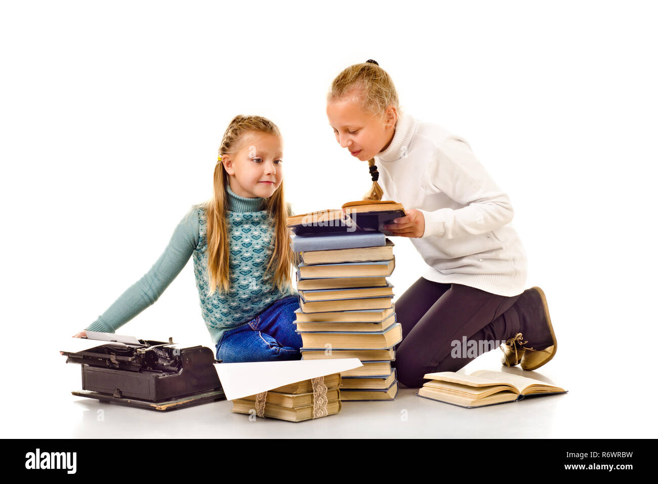 two little girls with a lot of books isolated on a white background ...