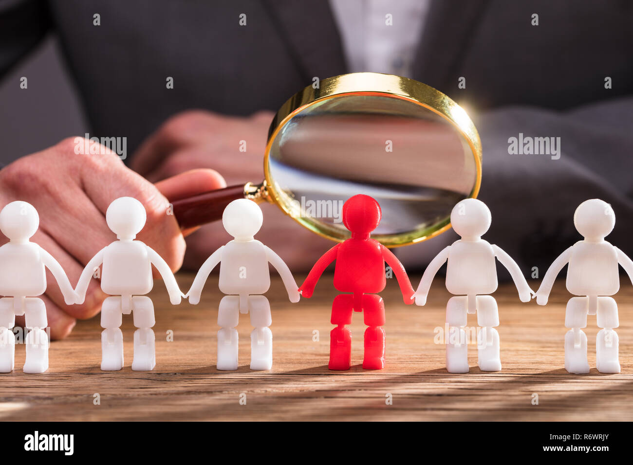 Hand Holding Magnifying Glass Over Red Human Figures Stock Photo - Alamy