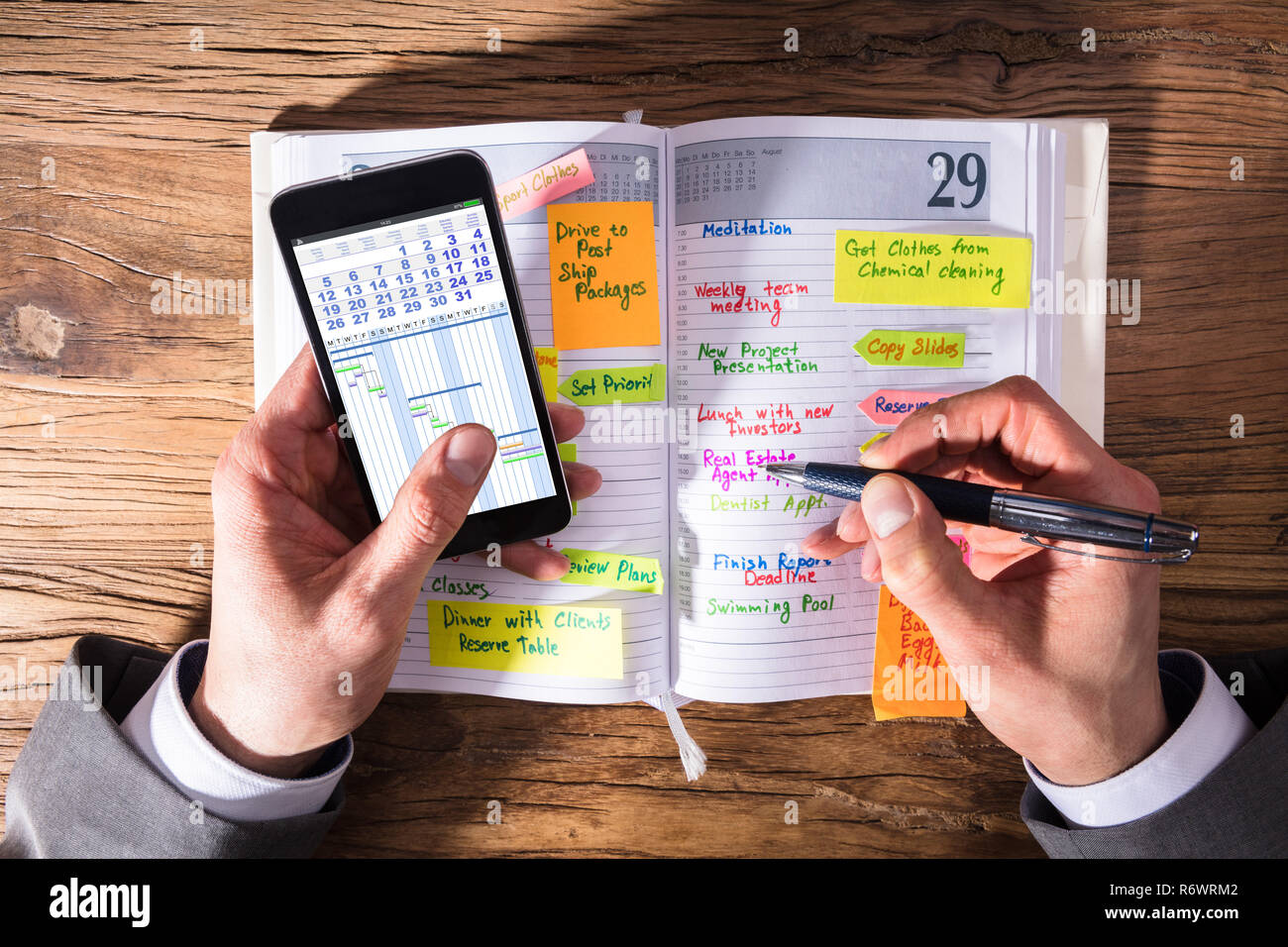Businessperson With Mobile Phone Writing Schedule In Diary Stock Photo ...