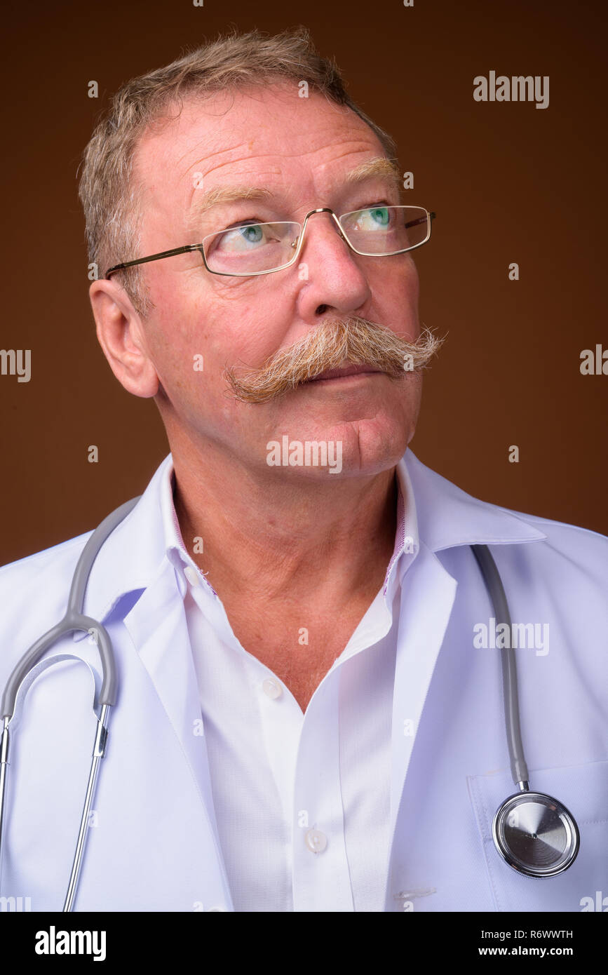 Face of senior man doctor with mustache thinking and looking up Stock ...